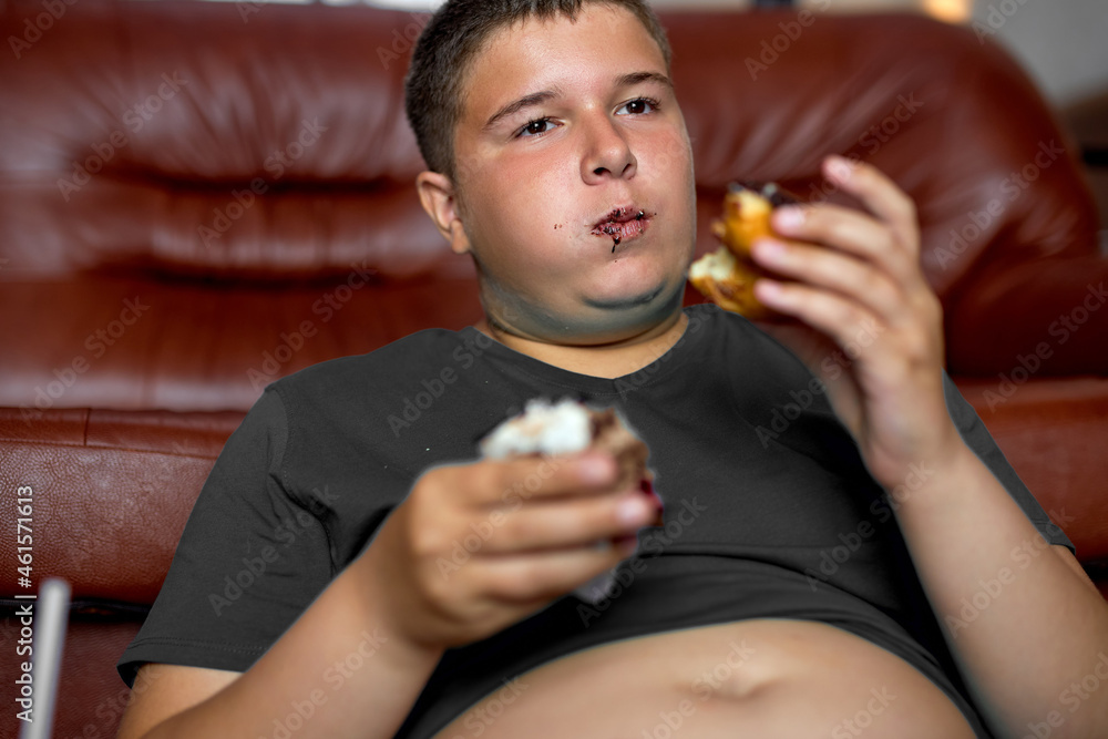 hungry caucasian fat boy is eating junk food at home while watching tv ...