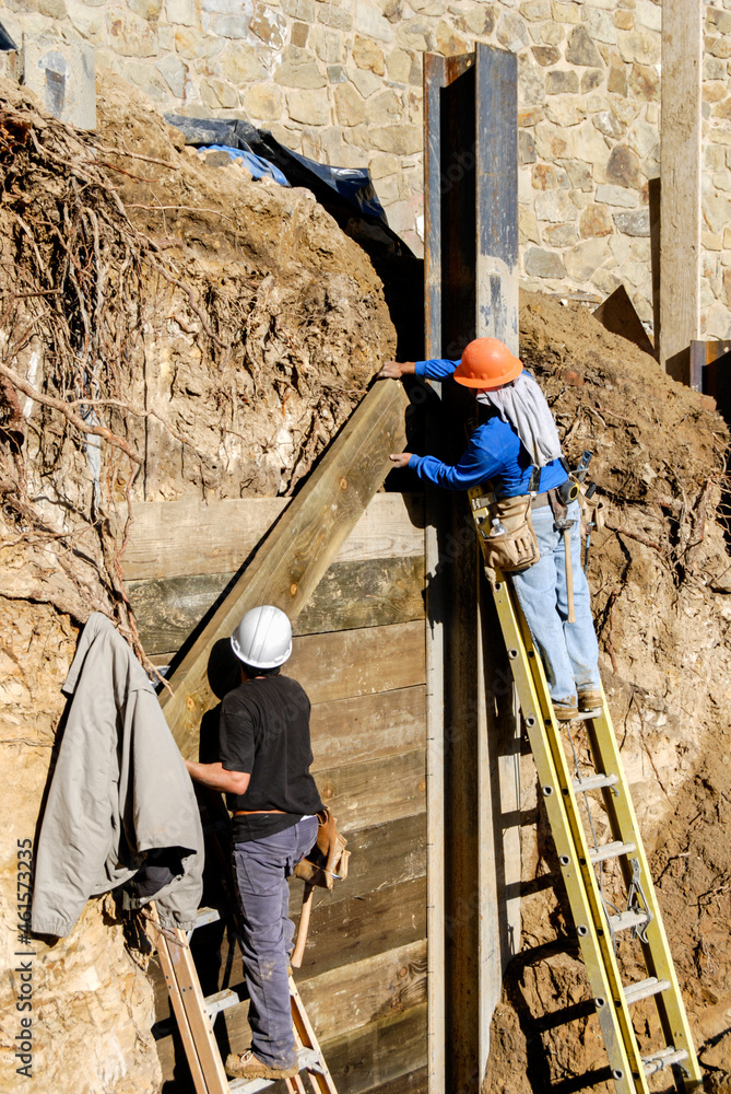 Construction workers installing lag boards between steel I-beams Stock ...