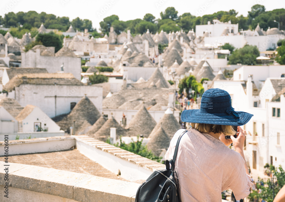 Blonde hair girl with hat and panoramic view of Trulli, traditional ...