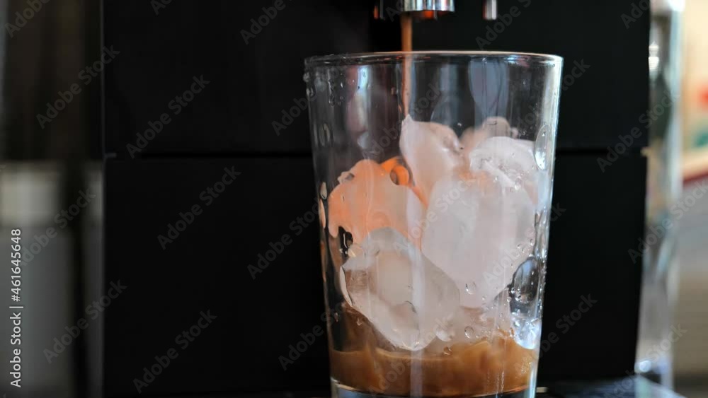 Ice Coffee preparation, pouring coffee in ice cubes from coffee machine ...