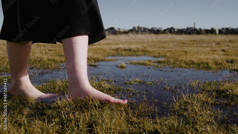 Girl woman walking bare feet foot moist wet grass water mud field ...