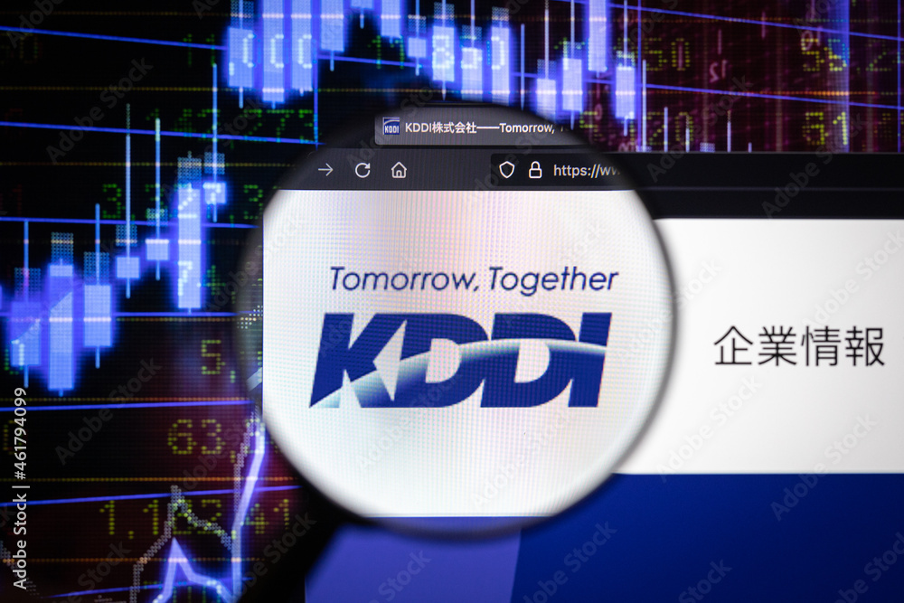 KDDI company logo on a website with blurry stock market developments in the background, seen on ...