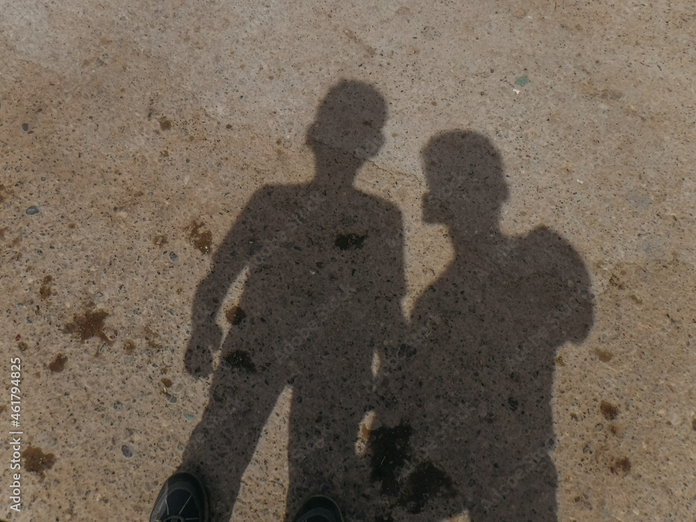 Shadows of two boys standing above grey dirt ground Stock Photo | Adobe ...
