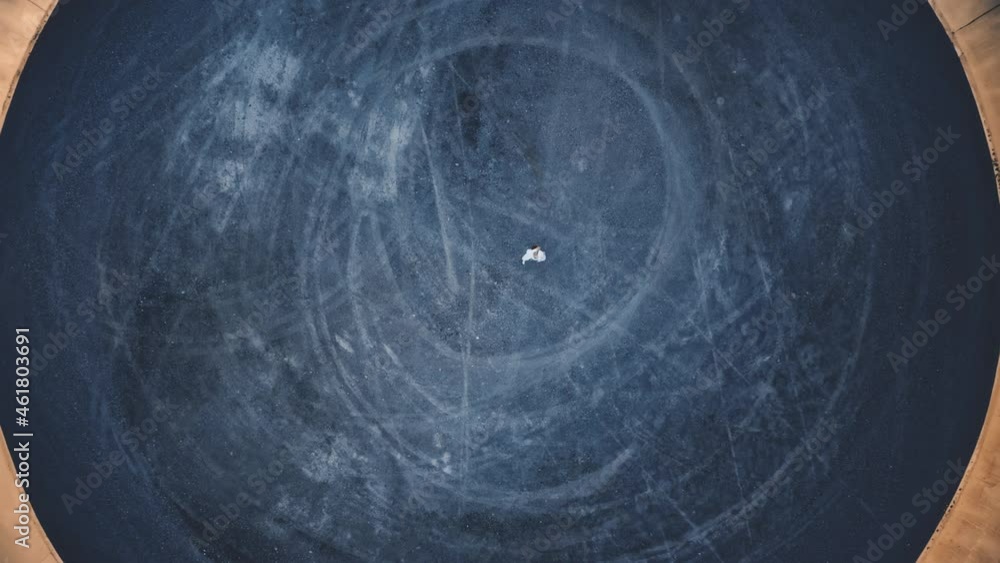 Woman waiting alien invasion in center on helipad. UFO round black ...