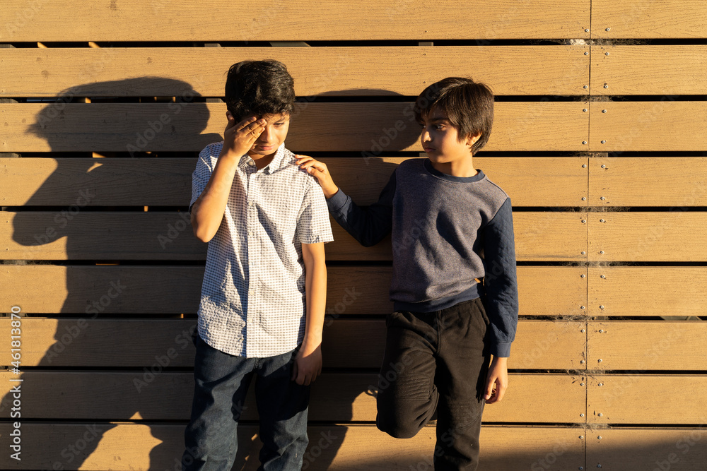 Caring for sad friend. Two young boys standing resolving conflict ...