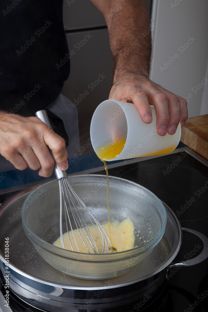 Chef cocinando al baño María con varilla en cocina. Chef cooking in a ...