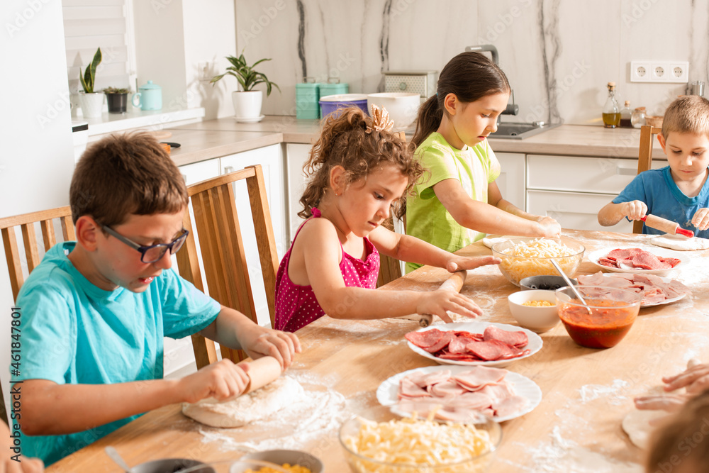 Happy kids sit at a table in the kitchen and make pizza Stock Photo ...