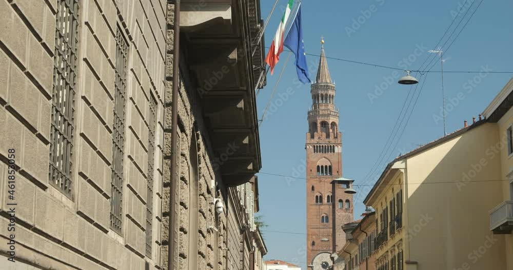 Torrazzo. Torrazzo of Cremona and palace with flags.A street in the ...