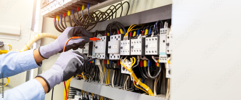 Electrical engineer using digital multi-meter measuring equipment to ...