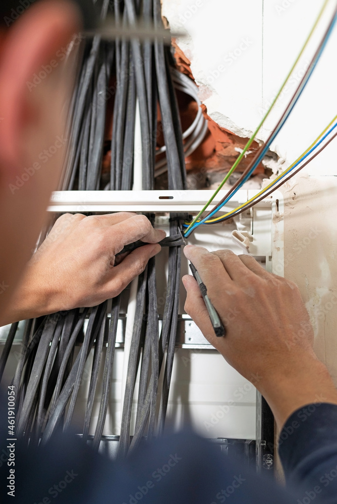 The electrician installs the electrical panel and prepares the wires ...