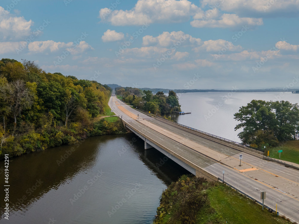 rural highway bridge over the river leading to lake with trees; blue ...