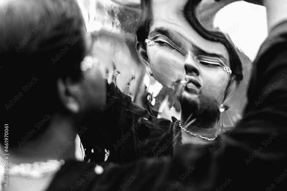 portrait of dark skinned Indian man looking into a distorted mirror ...