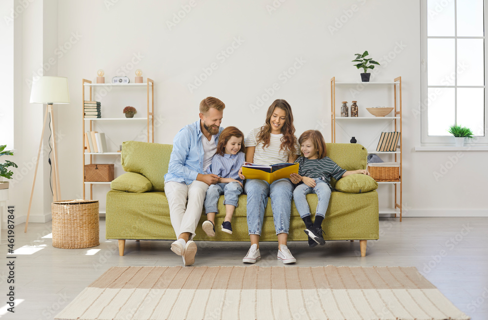 Happy family reading book at home. Mom, dad, little kids sitting ...