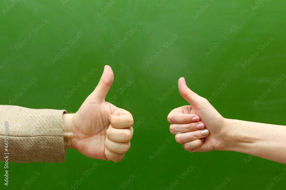 Male and female hand in the school classroom. Thumbs up shows that ...