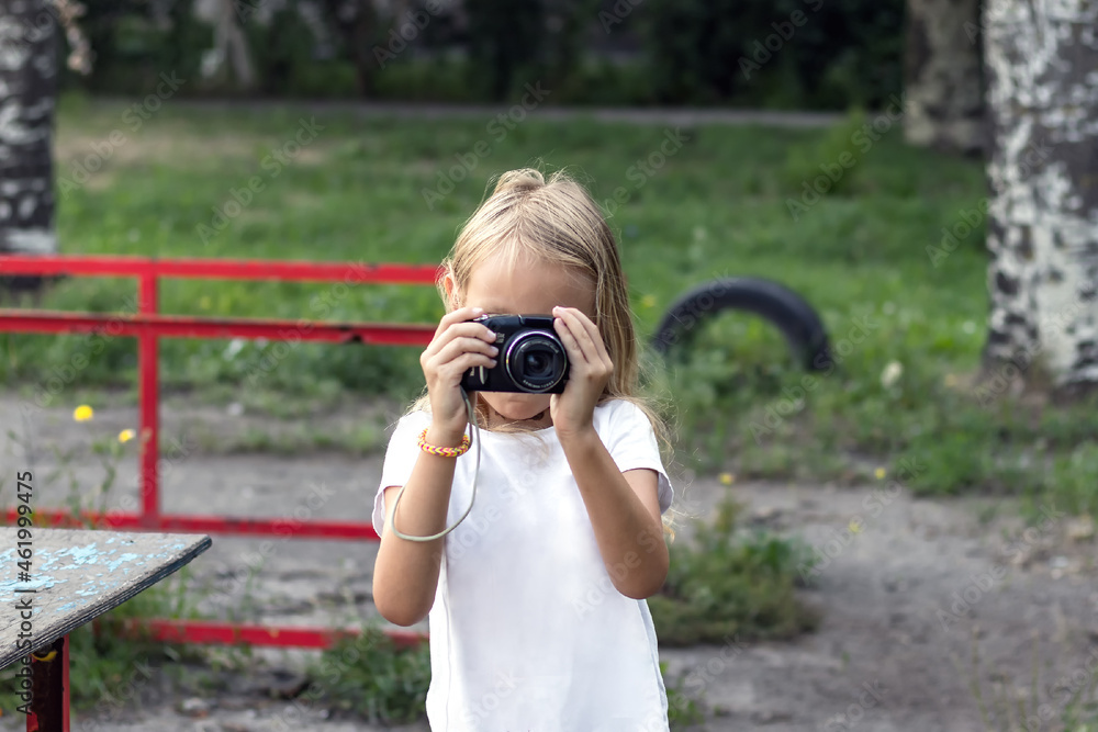 little girl takes pictures, holding the camera near her eyes, a ...