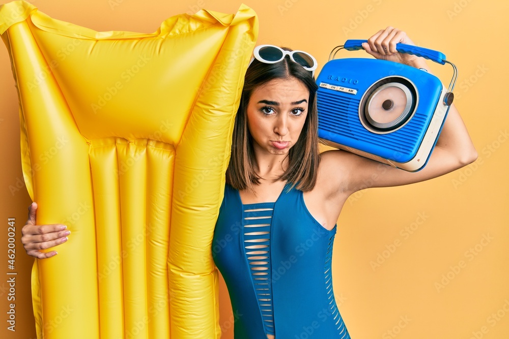 Young brunette girl wearing bikini holding boombox and float depressed ...