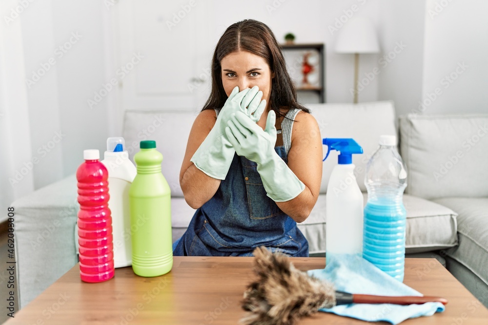 Young brunette woman wearing cleaner apron and gloves cleaning at home ...