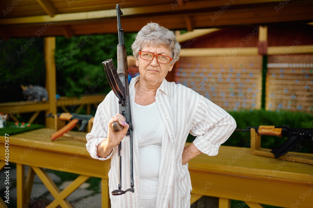 Pretty granny with gun poses in shooting gallery Stock Photo | Adobe Stock