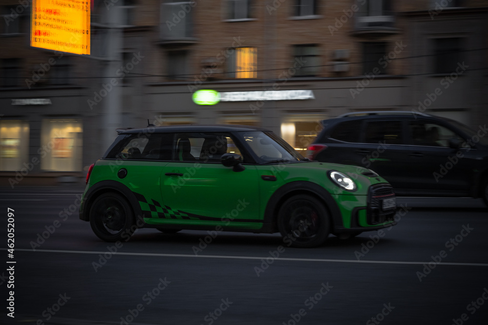 Side view rolling shot with green color car Mini Cooper moving on city ...