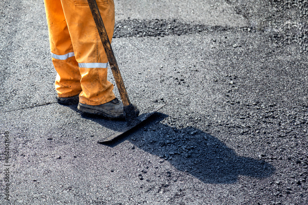 Road construction worker leveling fresh asphalt pavement Stock Photo ...