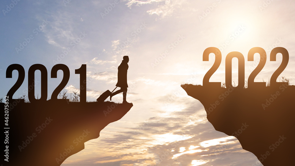 New Year 2022 is coming. Man with luggage goes from 2021 to 2022 year ...