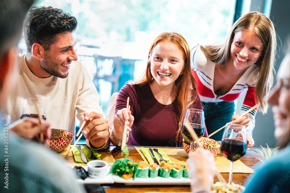 Foto de Happy friends eating with chopsticks at sushi restaurant - Food ...