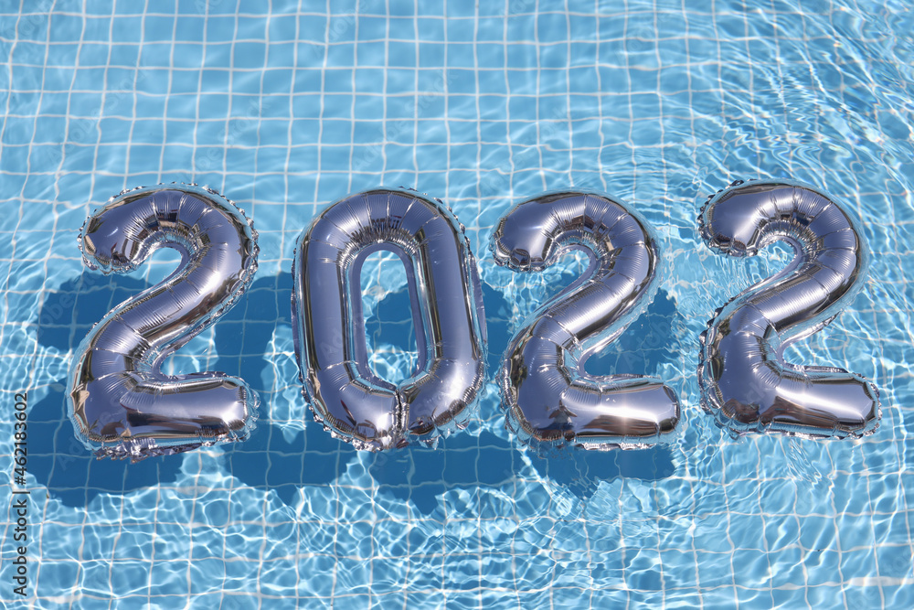 Silver helium balloons with numbers 2022 floating in swimming pool ...