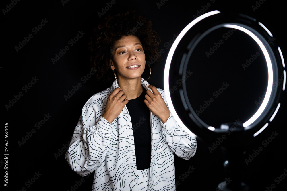 Female fashion model looking at ring light against black background ...