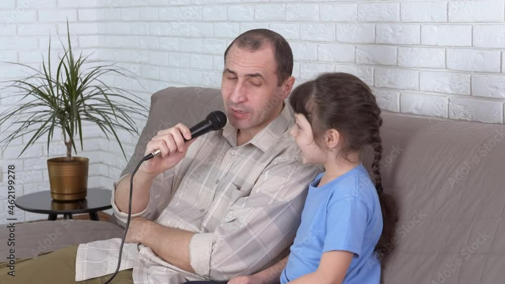 Family with singing microphone. A father sing a song on microphone with ...