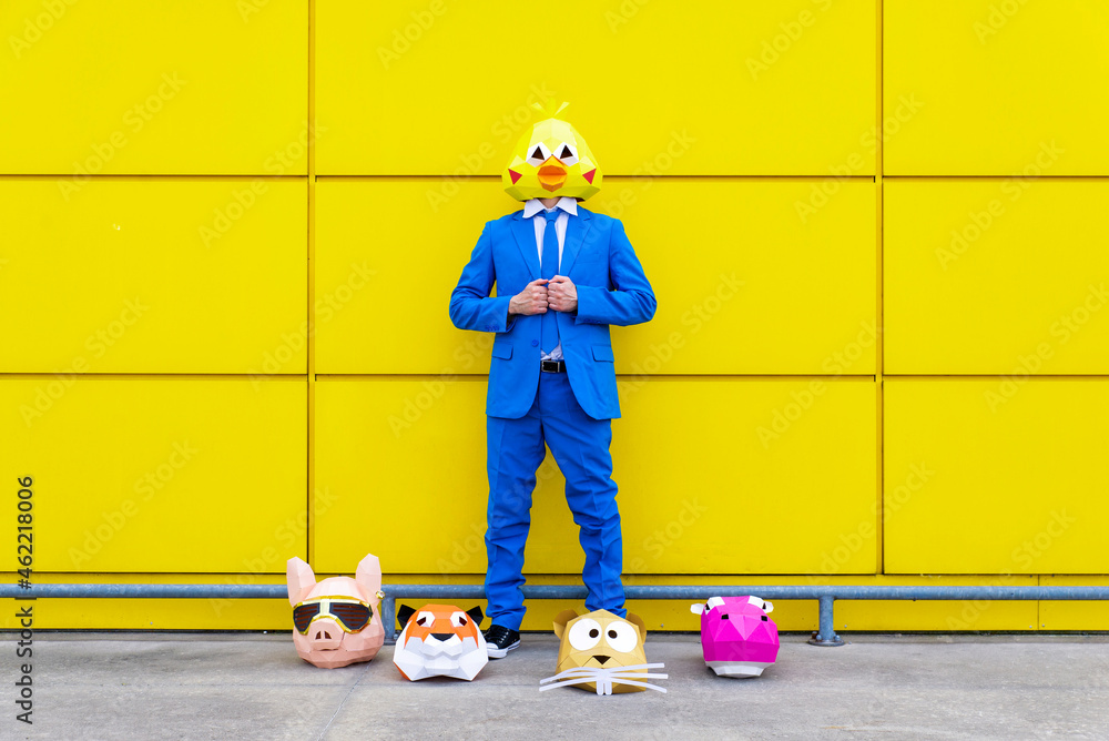 Man wearing vibrant blue suit and bird mask standing in front of yellow ...