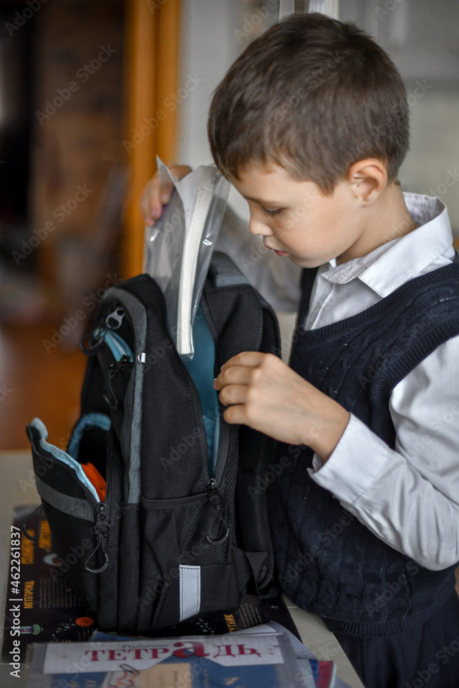 a boy in a school uniform collects a knapsack for school, a student ...