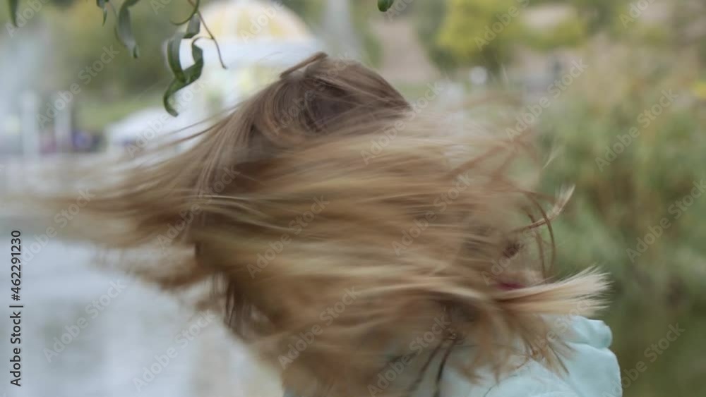 A young cheerful girl happily shakes her head, her hair flying in ...