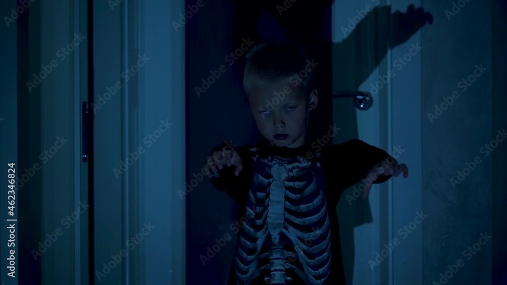 A boy in a skeleton costume in a scary house portrays a zombie and ...