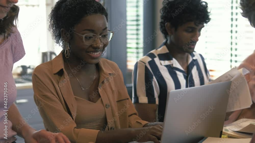 Happy smiley african woman student working using laptop with colleagues ...