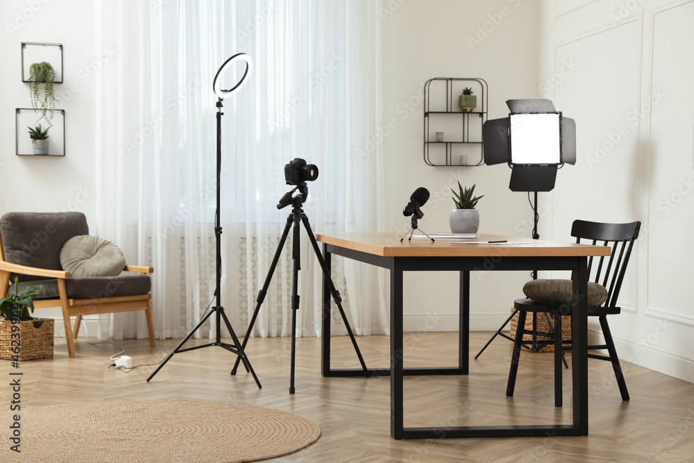 Camera and lighting equipment on tripods near table in room. Blogger ...