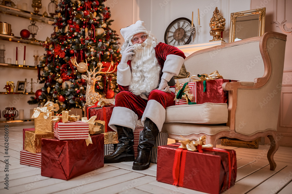 Santa Claus sitting on couch and talking on mobile phone near the ...