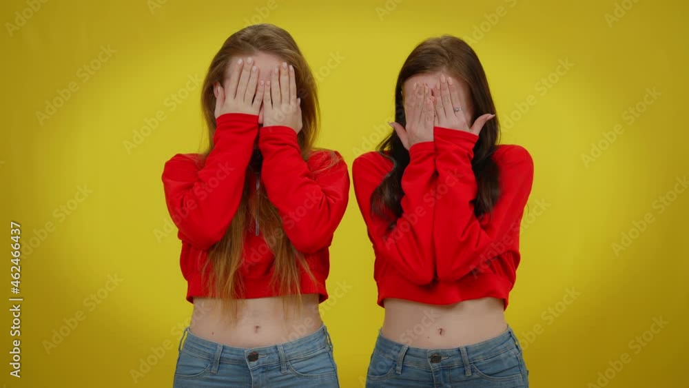 Frightened scared twin sisters closing face with hands shaking head ...
