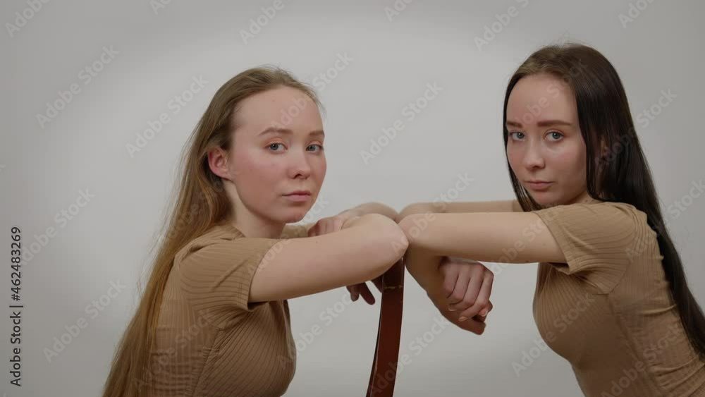 Concentrated young twin sisters looking at each other turning to camera ...