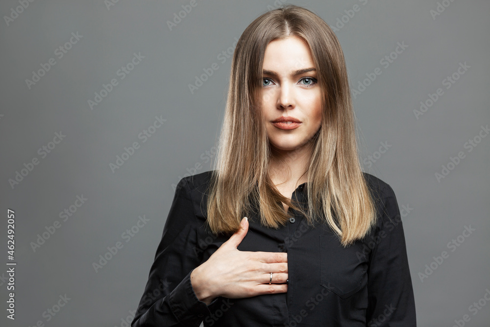 Young woman shows a hidden hand sign. Beautiful blonde in a black shirt ...