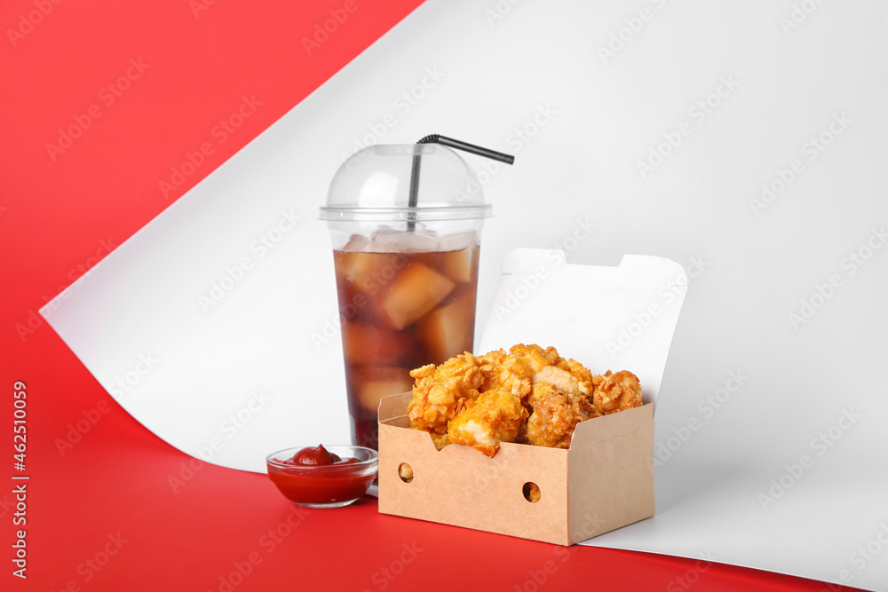 Paper box with fried popcorn chicken and plastic cup of cola on color ...