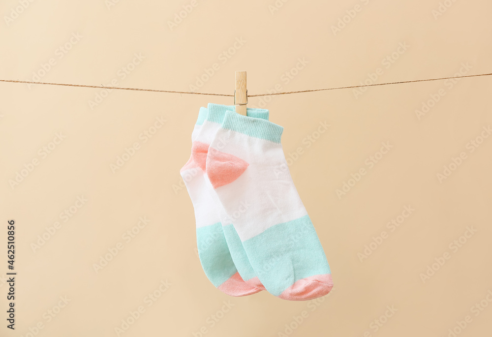 Pair of socks hanging on clothesline against color background Stock ...