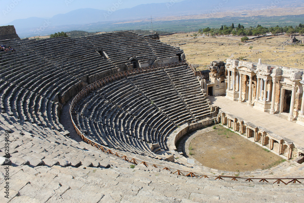 the ancient stone amphitheater and the remains of columns and portico ...