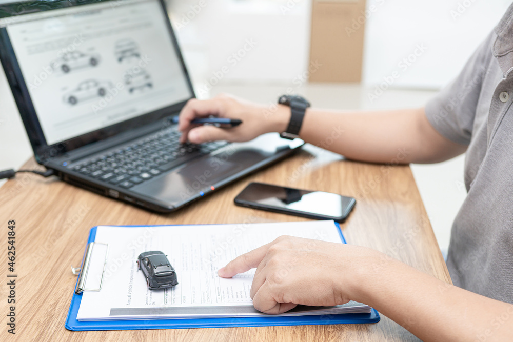 A man check data on check sheet document and use laptop computer in put ...