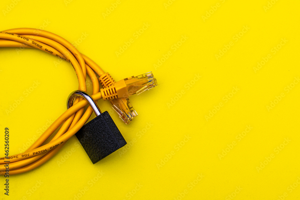 yellow internet cable twisted into a ring and a closed lock on a yellow ...
