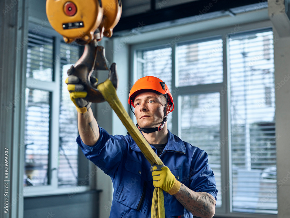 Industrial worker fixing hoist sling on indoor crane Stock Photo ...