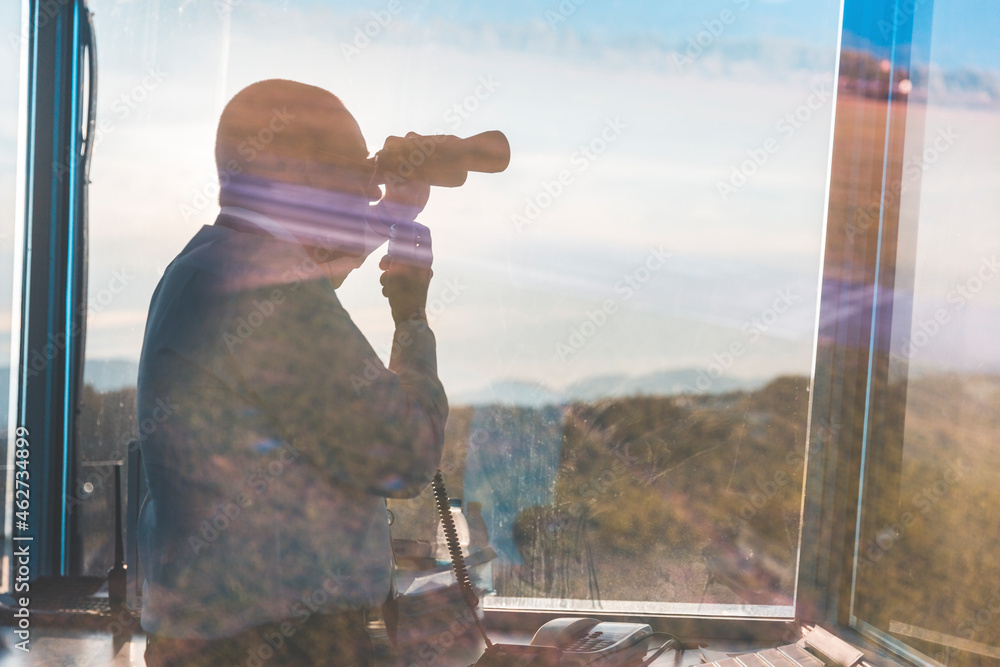 Pilot standing in control tower, using binoculars Stock Photo | Adobe Stock
