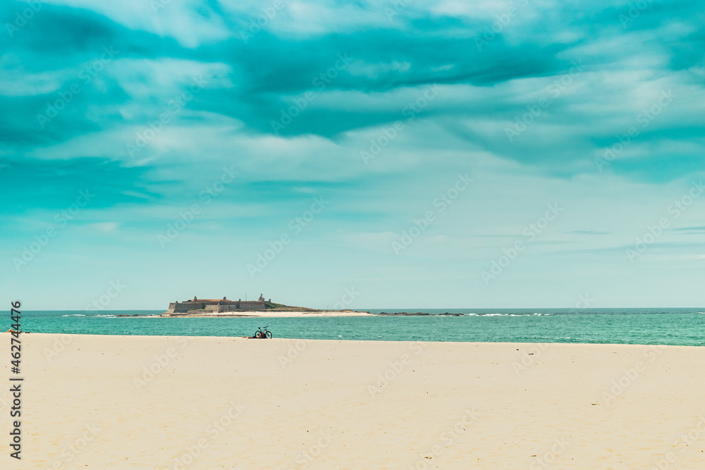 Bike on the sand and small island with the Fort of Ínsua in the ...