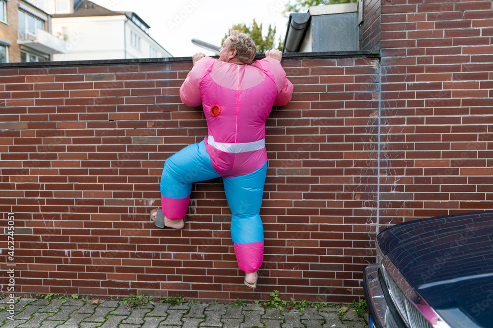 Man wearing pink bodybuilder costume climbing over a wall Stock Photo ...