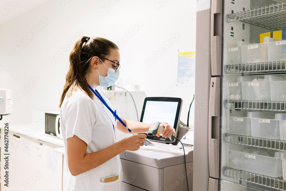 Female doctor scanning id card while standing in pharmacy at hospital ...