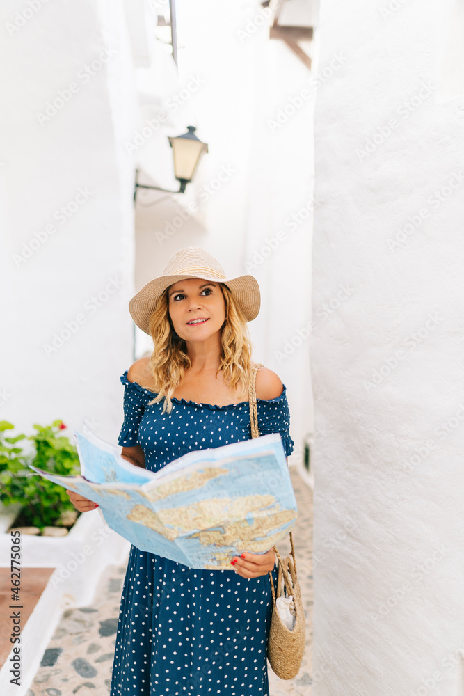 Female tourist wearing hat holding map while standing in Binibeca ...